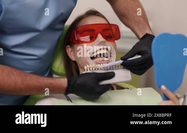 Teeth shades, Dental procedure, Dental visit. Patient holds hand mirror ...