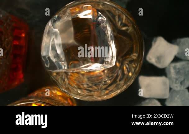 Super Slow Motion Shot of Ice Cube Falling into Glass with Alcohol at ...