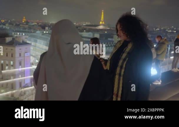 Two Muslim girls take pictures in front of the Eiffel Tower at ...