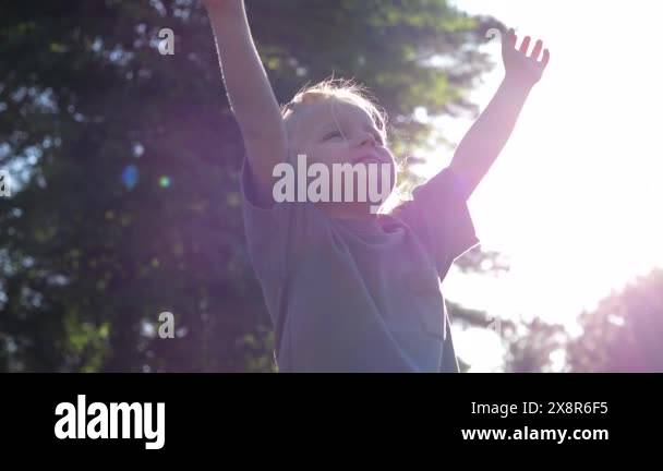 Girl greets sun by smiling and raising hands up. Sun illuminates it ...