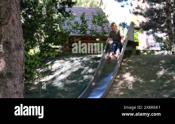 Girl happily slides down slide and runs back up again to ride. Slide in ...