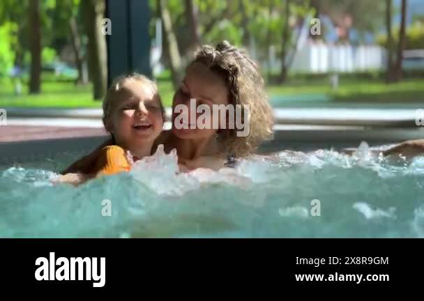 Mom and daughter have fun at spa, splashing around in healing spa ...