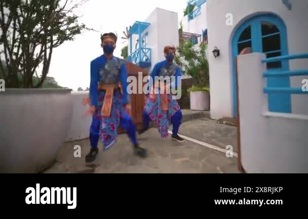 Two joyful dancers in colorful outfits and face masks performing a ...