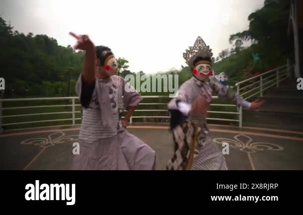 Two performers in traditional masks and costumes posing outdoors with a ...