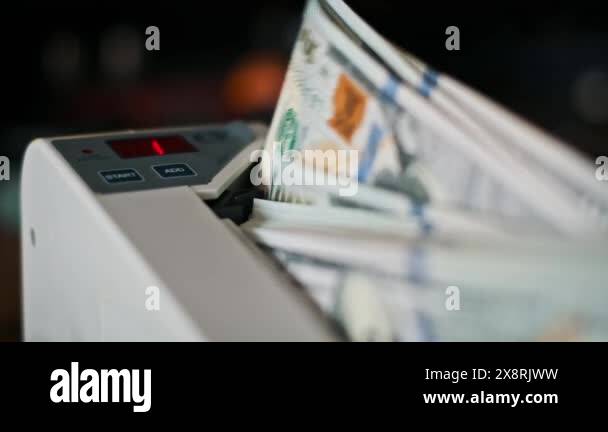 A close-up view captures the precise counting of US dollar bills by a ...