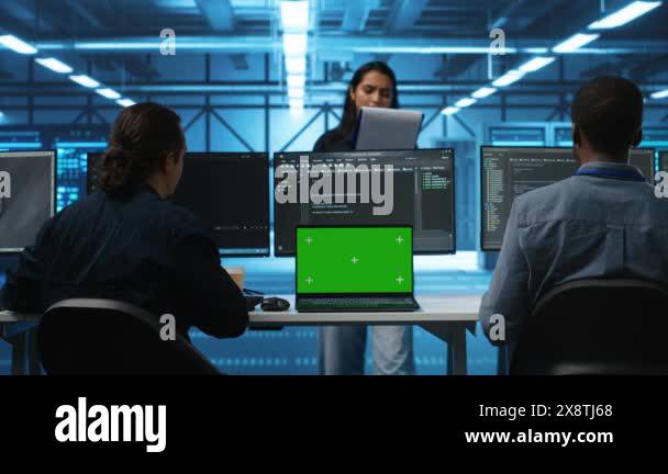 Multiethnic engineers working in high tech server hub, using green screen laptop and PCs to ...
