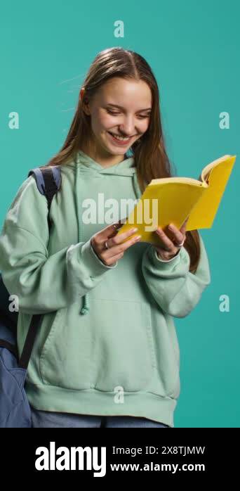 Vertical video Young girl reading book, enjoying hobby, being ...
