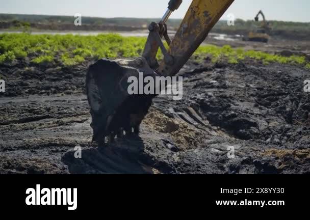 Excavator bucket scoops sludge preparing area for setting water supply ...