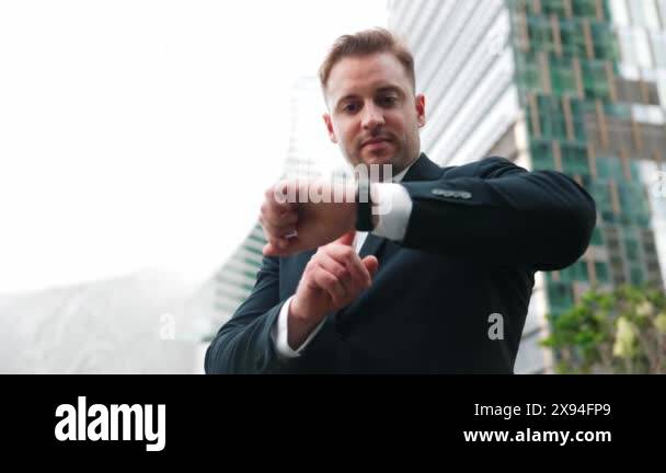 Low angle camera of businessman looking at watch to remind about time ...