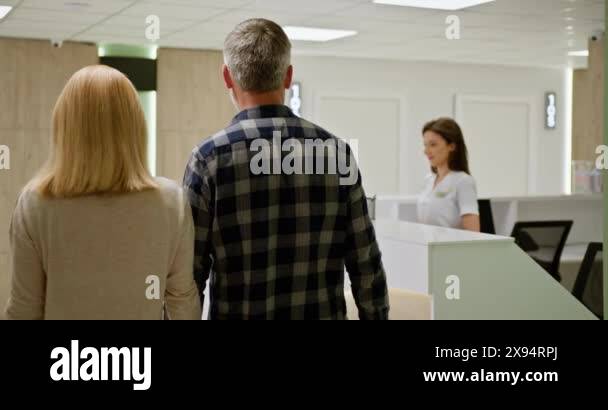Receptionist talking to couple patients in front of reception counter ...