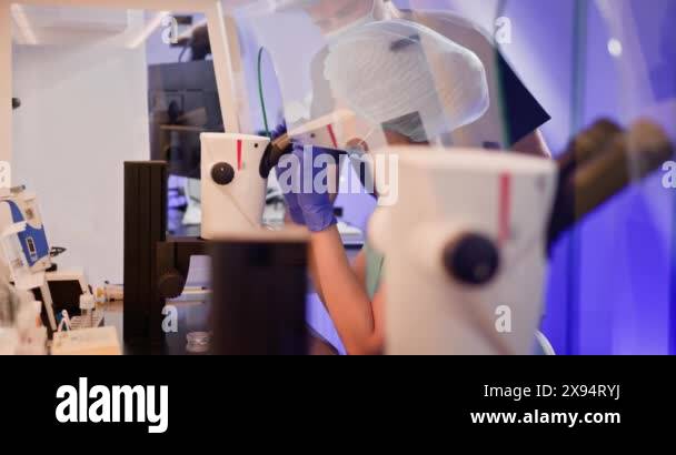Laboratory worker examining samples under microscope in clinic ...