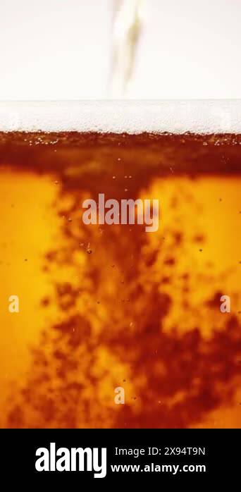 Golden drink. Foamy lager beer pouring into glass, bubbles rising ...