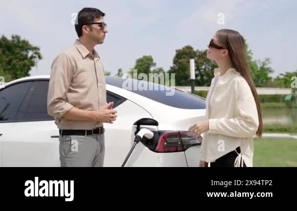 Young couple recharge electric cars battery from charging station in ...