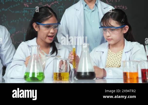 Smart teacher support and look after young diverse children doing experiment together. high ...