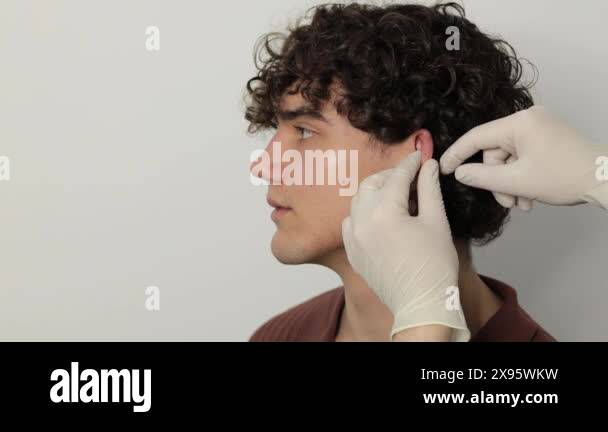 4k video Surgeon doctor examines ear of male patient before otoplasty ...
