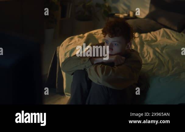 Handheld footage of gen Z guy sitting on floor in front of TV and ...