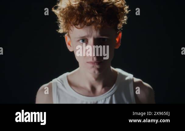 Closeup studio portrait of ginger haired gen Z guy in undershirt ...