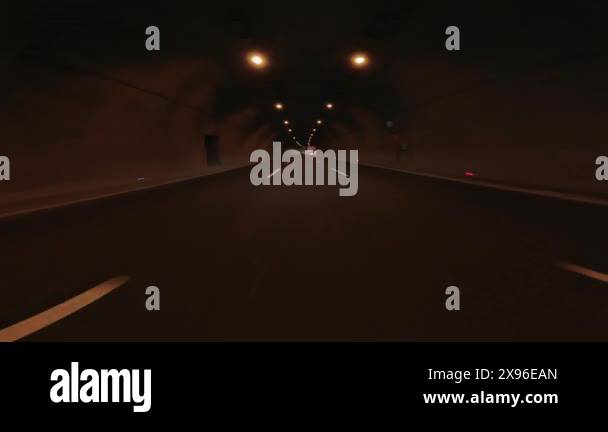 First person view as car drives through tunnel in mountains underground ...