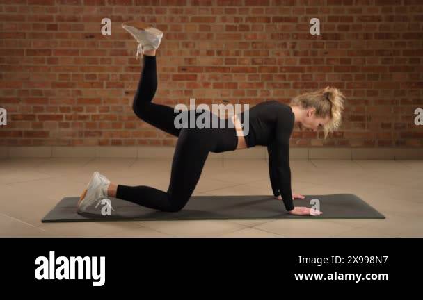 This skilled fitness trainer exhibits dynamic donkey kick pulses on the ...