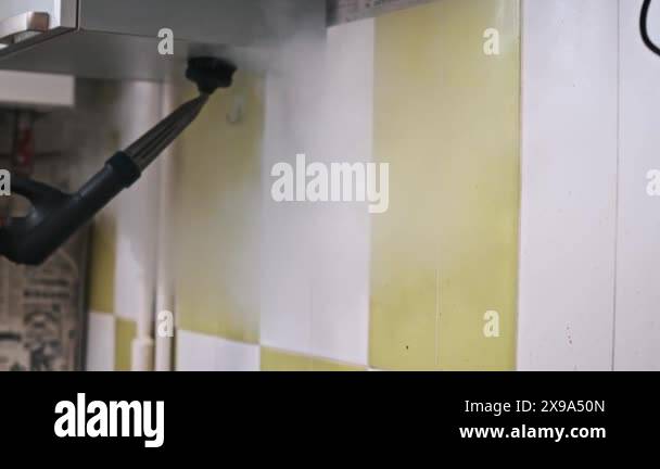 A handheld steam cleaner blasts hot steam onto the underside of kitchen ...