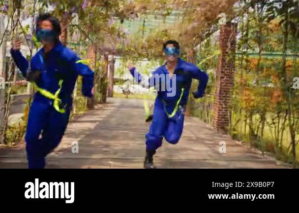 Two people in blue overalls and safety goggles playfully dancing in a ...