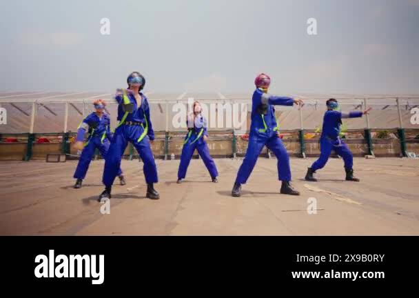 Group of workers in blue uniforms and hard hats performing synchronized ...