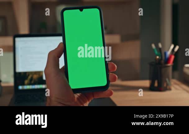 Freelancer hand holding greenscreen mobile phone at office workplace ...