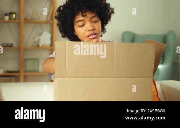 African girl unpacking delivery looking in box. Happy woman opening ...