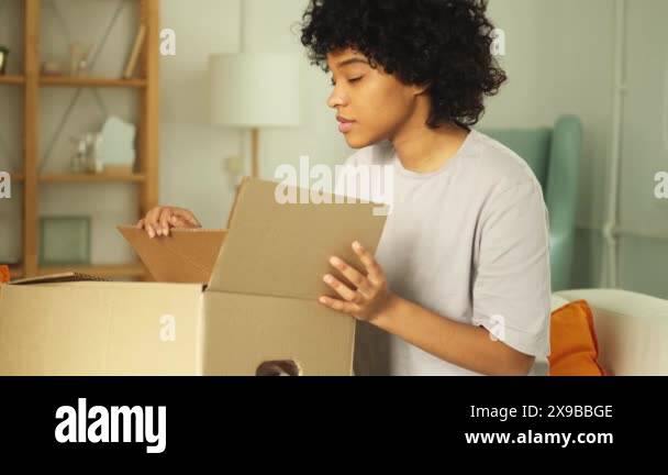 African girl unpacking delivery looking in box. Happy woman opening ...