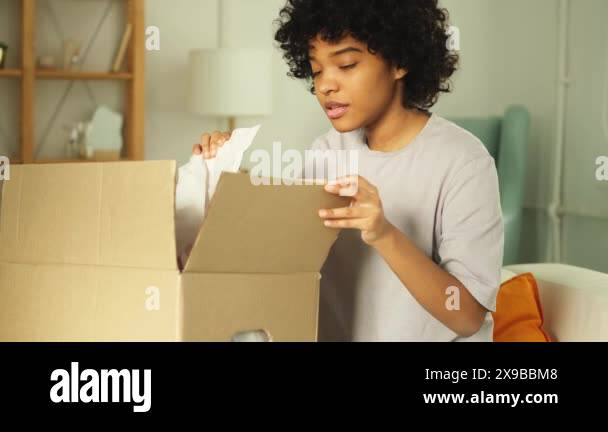 African girl unpacking delivery looking in box. Happy woman opening ...
