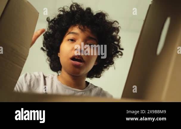 Inside of cardbox bottom view. African girl unpacking delivery looking ...