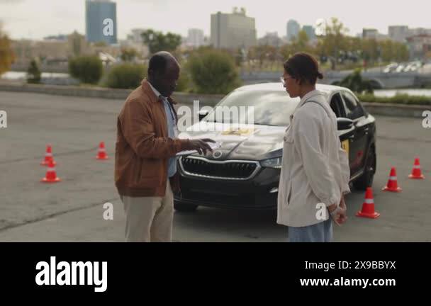 Medium of mature male Black driving coach congratulating young female ...