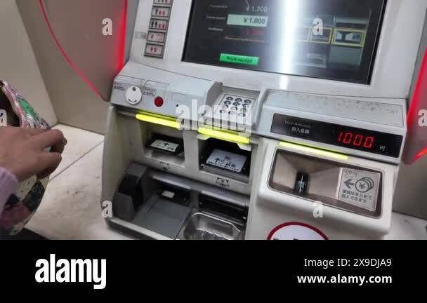 Closeup passenger hand adding Japanese yen into ticket vending machine ...