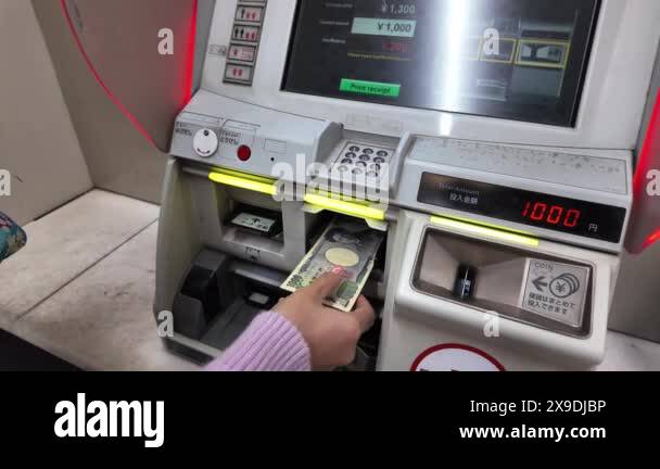 Closeup passenger hand adding Japanese yen into ticket vending machine ...