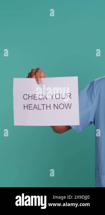 Vertical video Portrait of upbeat nurse smiling, holding sign urging ...