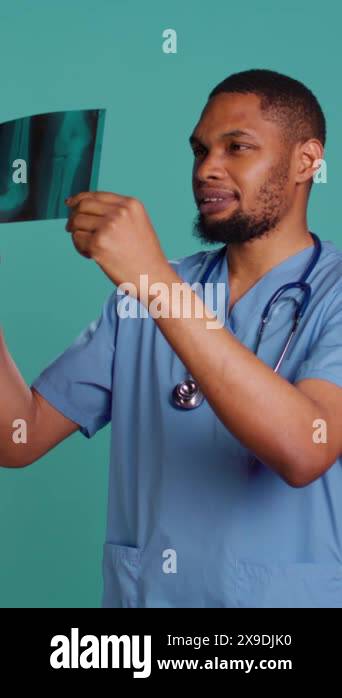 Vertical video Male nurse analyzing radiology x ray scan to provide ...