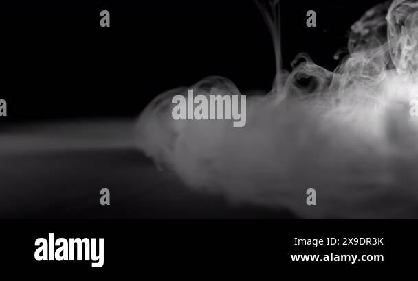 A stream of smoke lands and spreads on a flat surface. The smoke ...