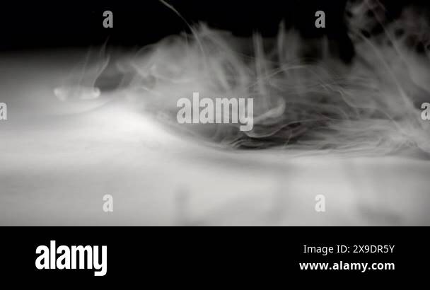 A monochromatic view of smoke wafting across a surface. The smoke ...