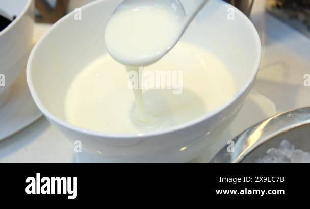 Close up milk pouring into glass jar. Preparation of homemade yogurt in ...