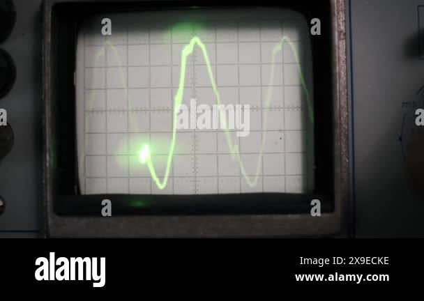 Close-up, the camera zooms out from a vintage oscilloscope screen as a ...