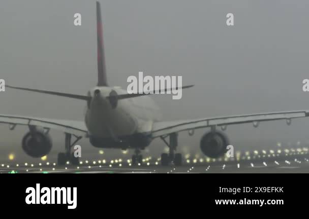 Airplane taking off from a runway, with fog and runway lights visible ...