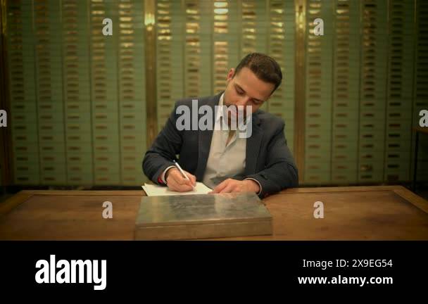 A businessman sits in a secure vault room revising important documents ...