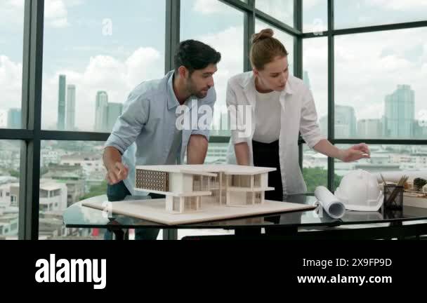 Cooperative architect engineer team working together to measure house model by using pencil ...