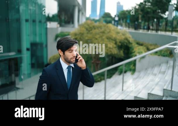 Smiling handsome business man looking at time and walking up stair at ...