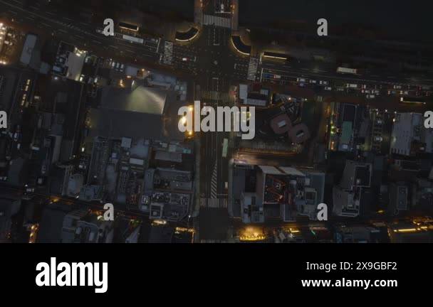 Fly above road intersection in evening city. Streets illuminated by ...