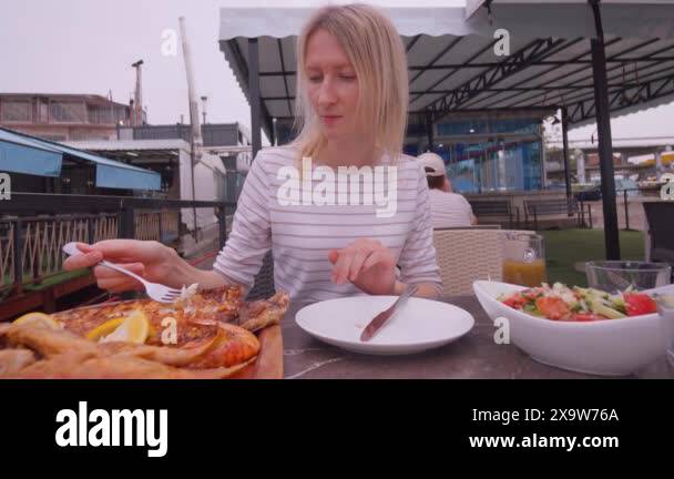Girl eating fish for lunch in restaurant Happy woman with baked sea ...