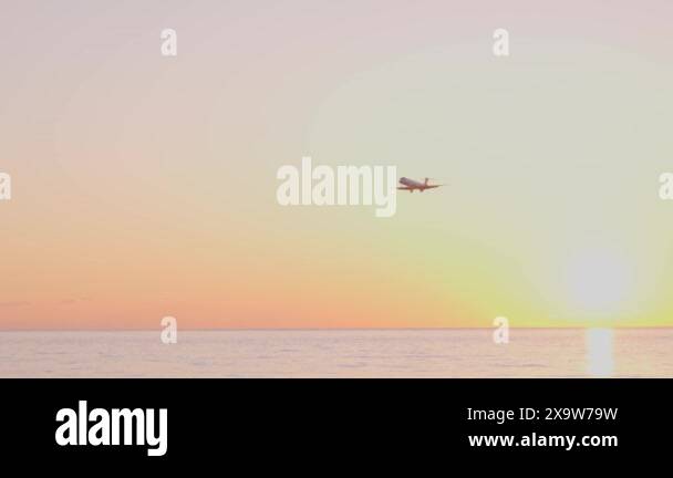Flight of aircraft over ocean before landing in evening. Rear image ...