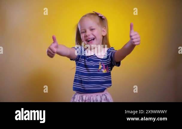 Young girl giving thumbs up and cheerfully laughing and dancing. Happy ...