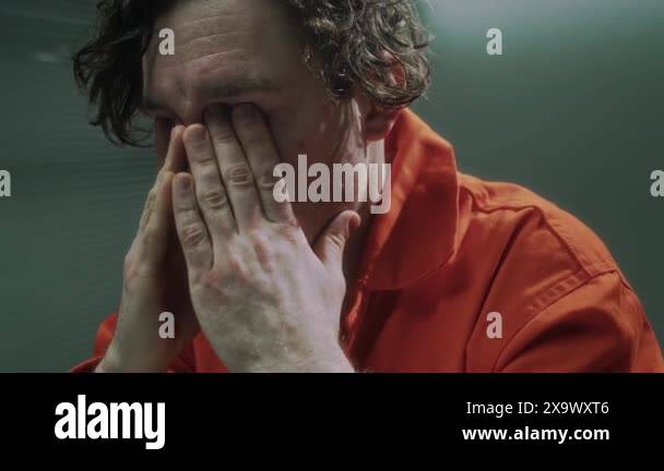 Close-up shot of young Caucasian male serial murder suspect in orange ...