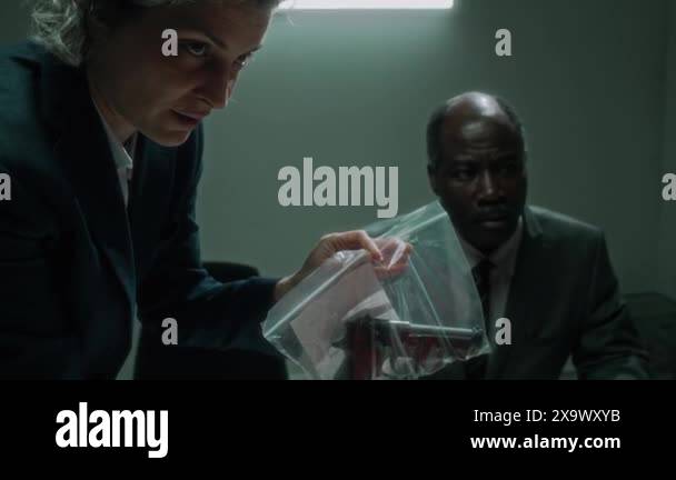 Close-up tilt shot of Caucasian female federal agent holding up murder ...